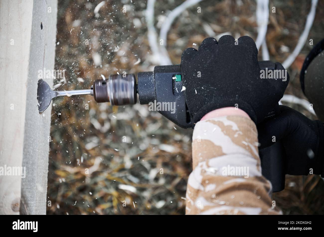 Man building wooden frame house. Close up of male worker drilling hole ...