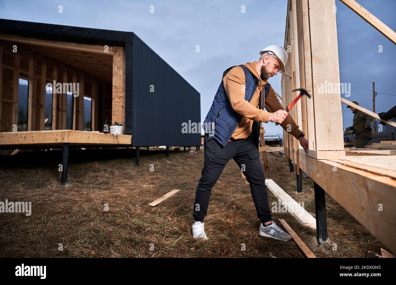 Man worker building wooden frame house on pile foundation. Carpenter ...