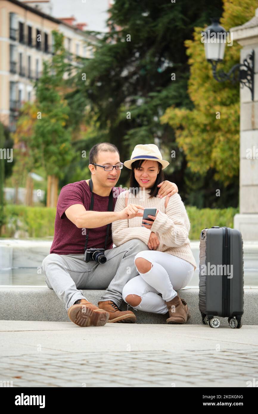 Multiracial couple of tourists consulting a city guide in their ...