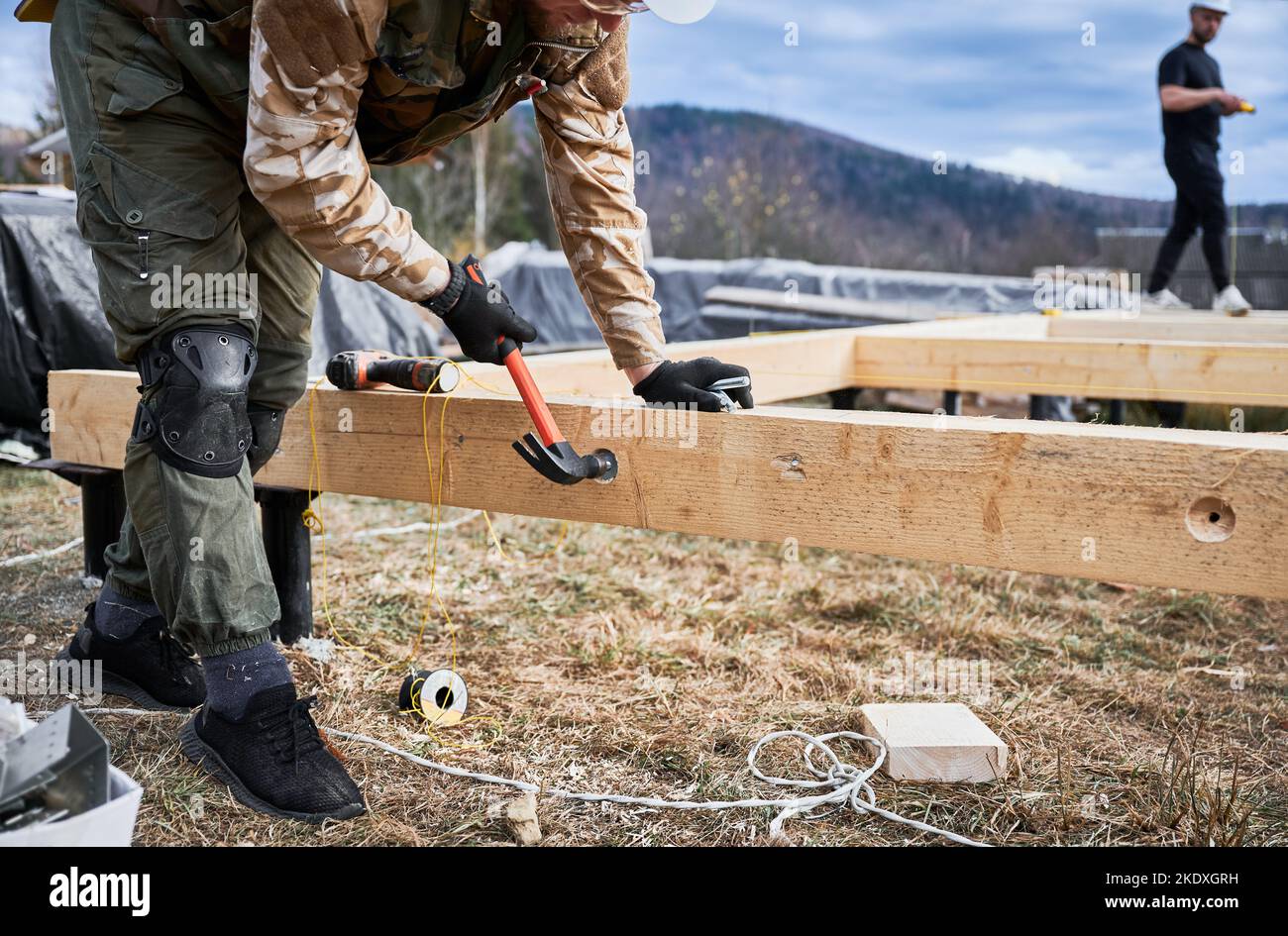 Man worker building wooden frame house on pile foundation. Carpenter ...