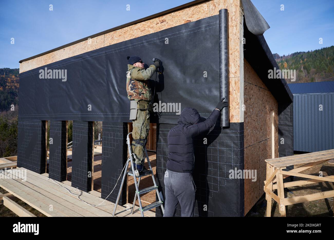 Male builders installing waterproof membrane on the wall of future ...