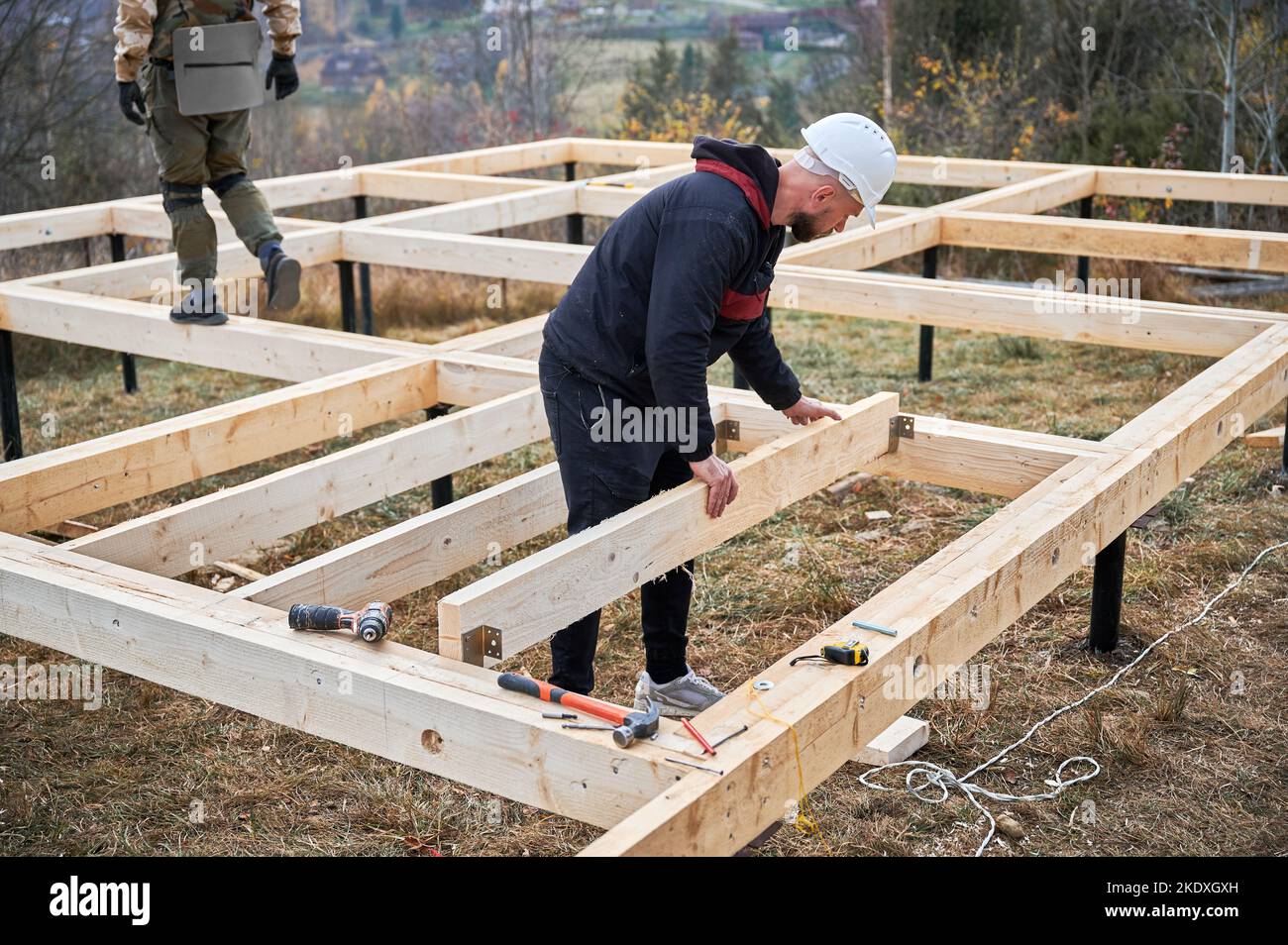 Man worker building wooden frame house on pile foundation. Carpenter ...