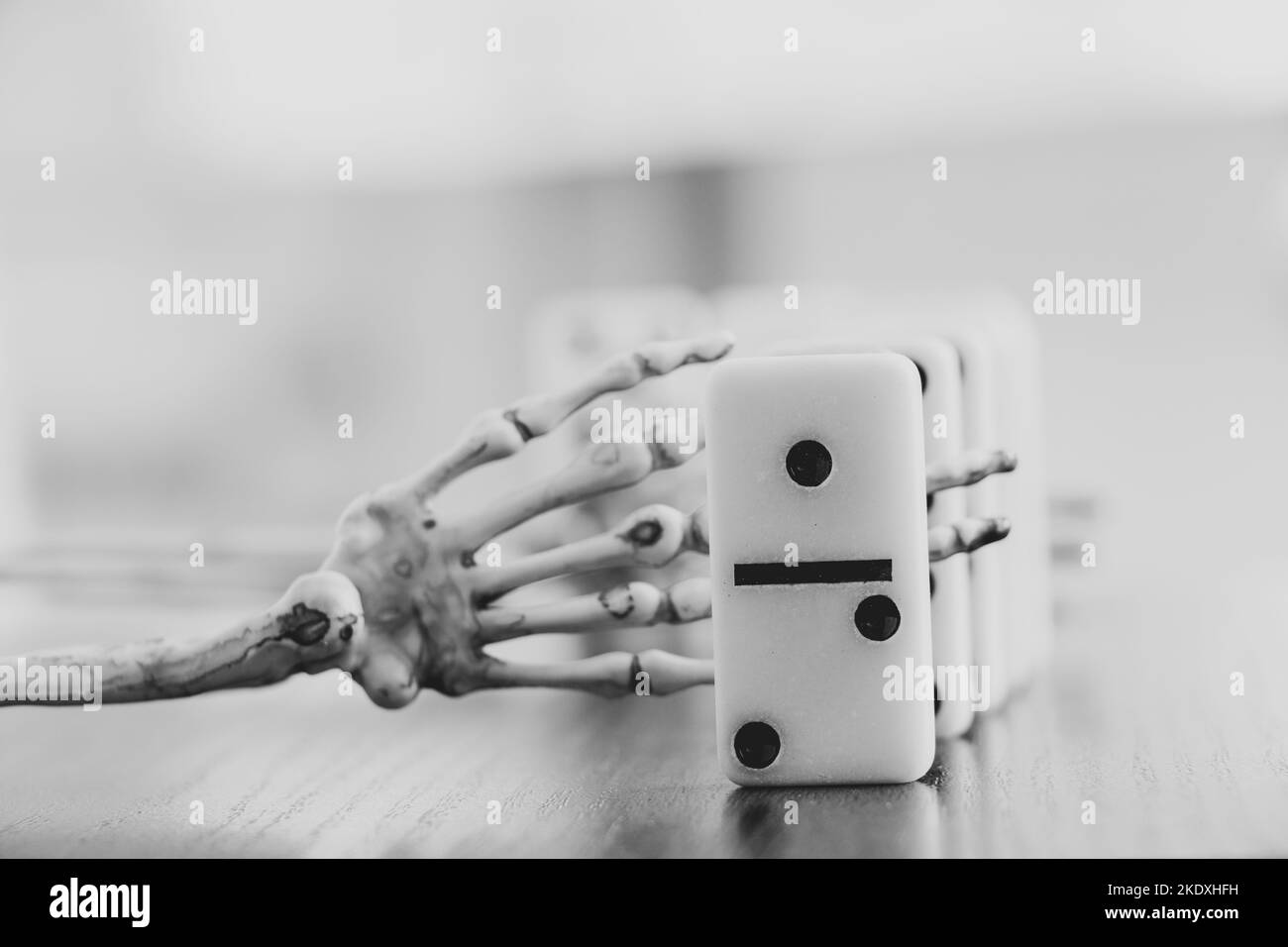 Skeleton hand and domino bones are on the table, black and white photo ...
