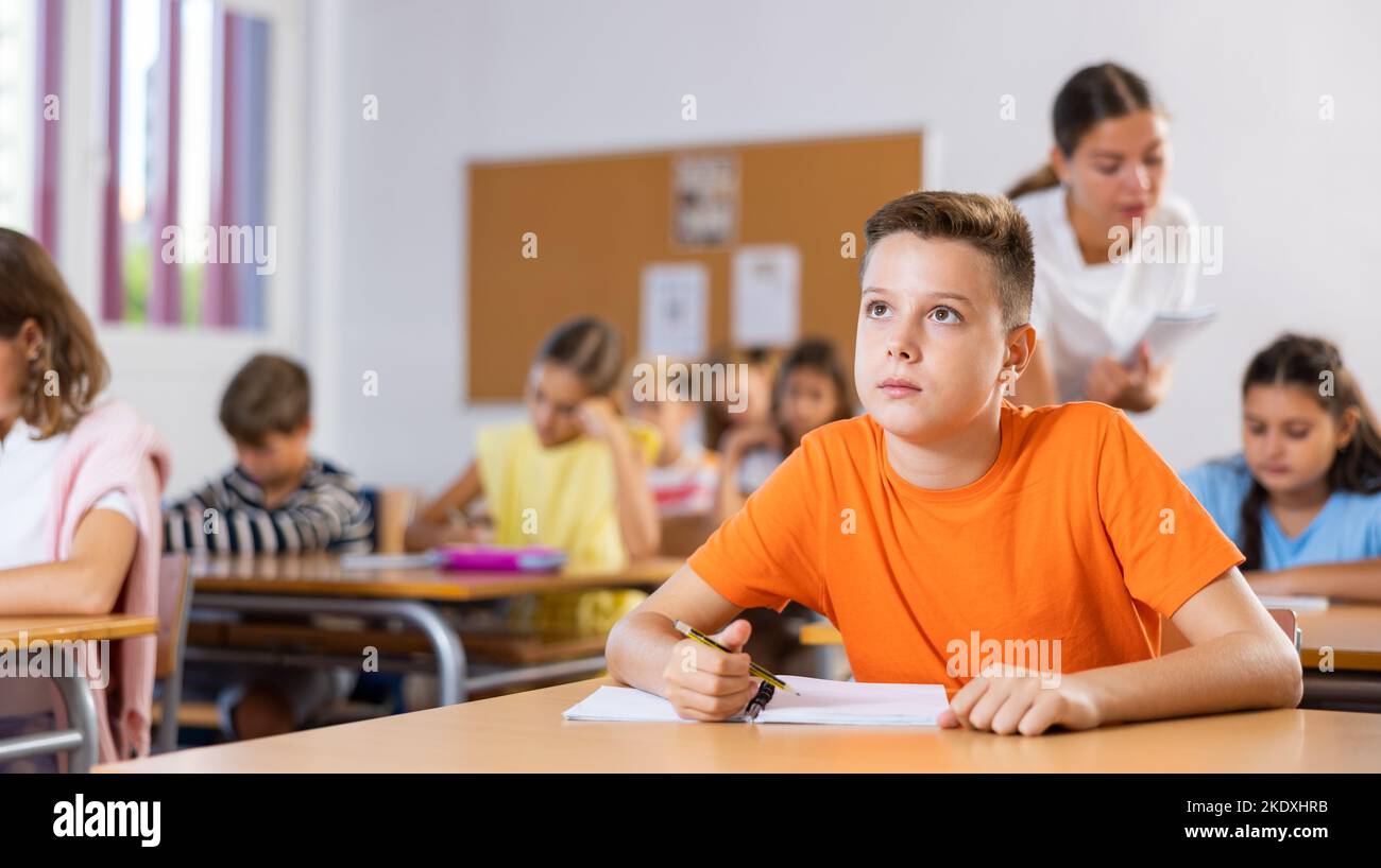 School boy sitting at the desk in classroom at lesson in primary school ...