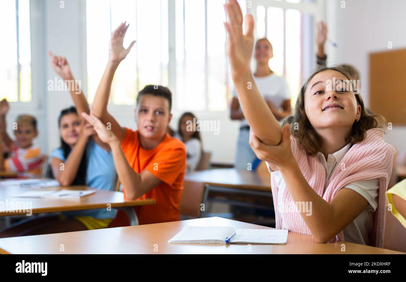 Girl raising her hand during lesson in school Stock Photo - Alamy