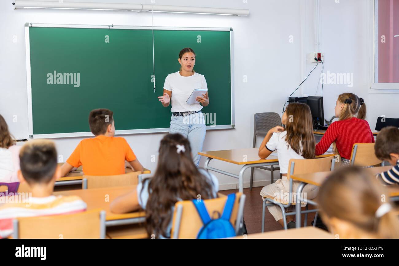 Woman teacher explaining new theme to children during class in primary ...