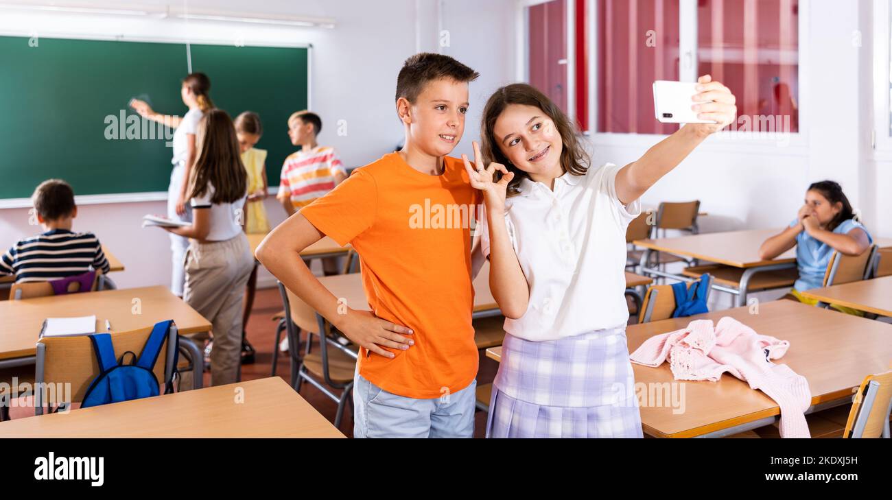 Cheerful tween schoolgirl taking selfie on phone with classmate in ...