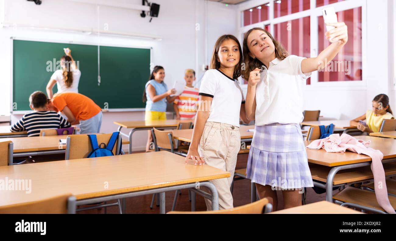 Two girls taking selfies in classroom during recess Stock Photo - Alamy