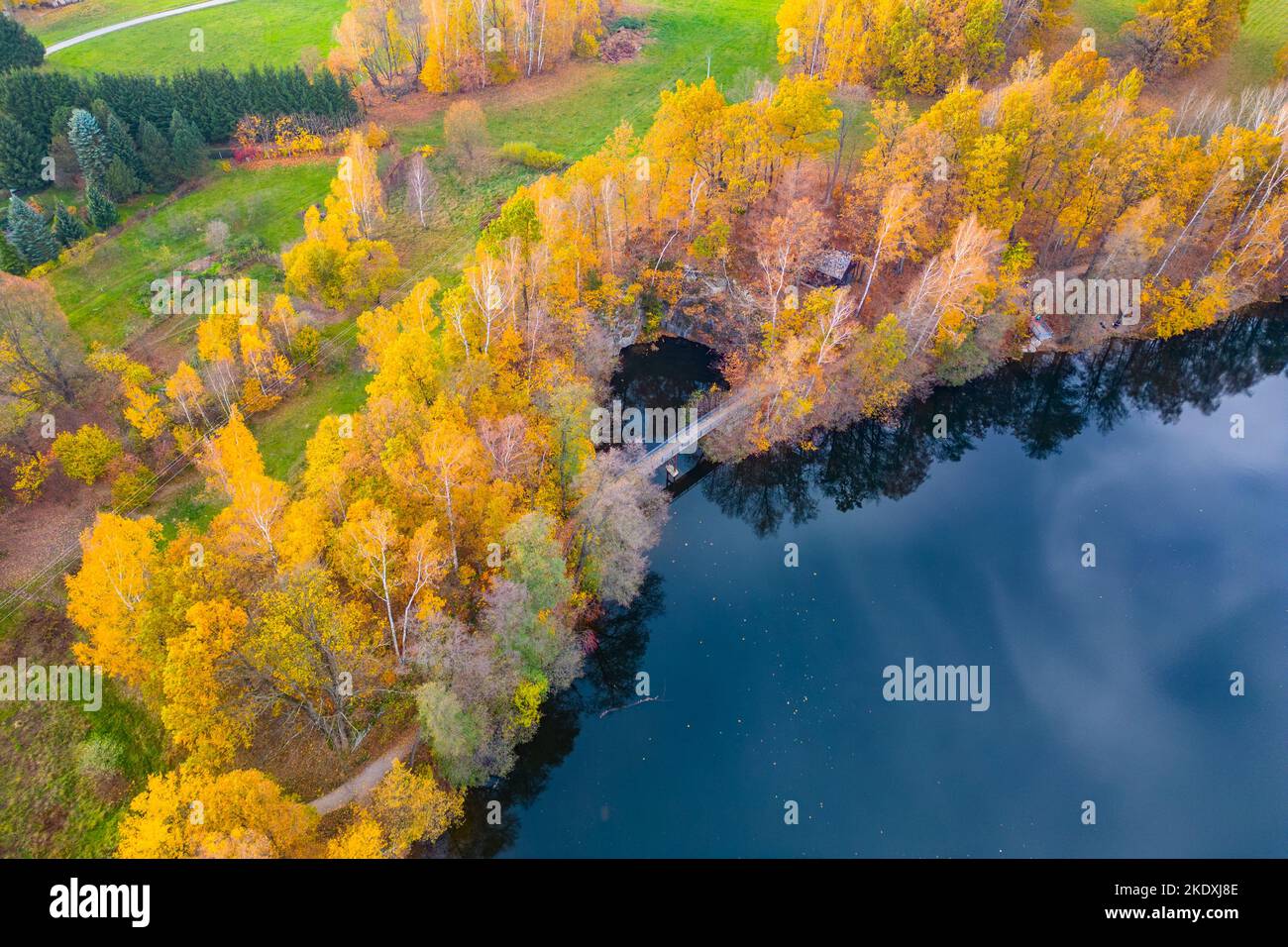 Tourist path through vibrant colored forest and bridge over blue water ...