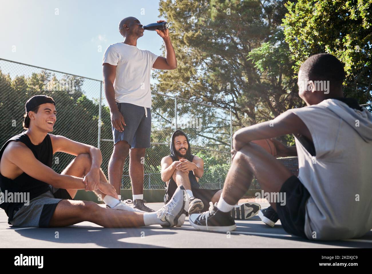 Friends, sports and team relax after training on basketball court ...