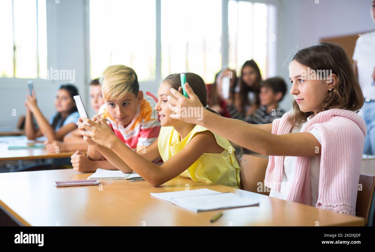 Schoolkids photographing with phones in classroom Stock Photo - Alamy