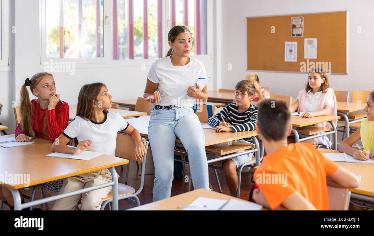 Teacher reading lecture to schoolkids in classroom Stock Photo - Alamy