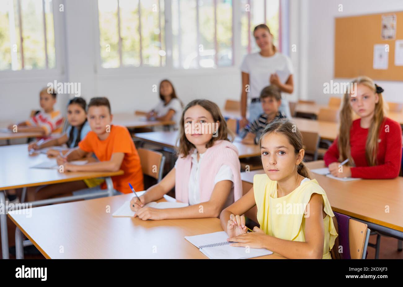 School kids with pens and notebooks studying in classroom with teacher ...