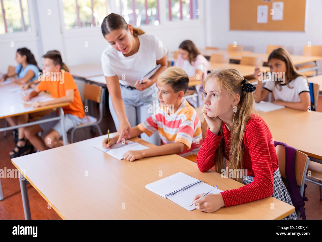 Group of preteen schoolchildren diligently making notes in class Stock ...