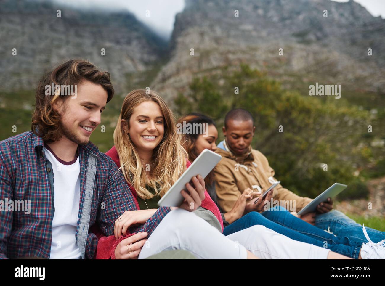 Time for a status update. a young man showing his tablet to a friend ...