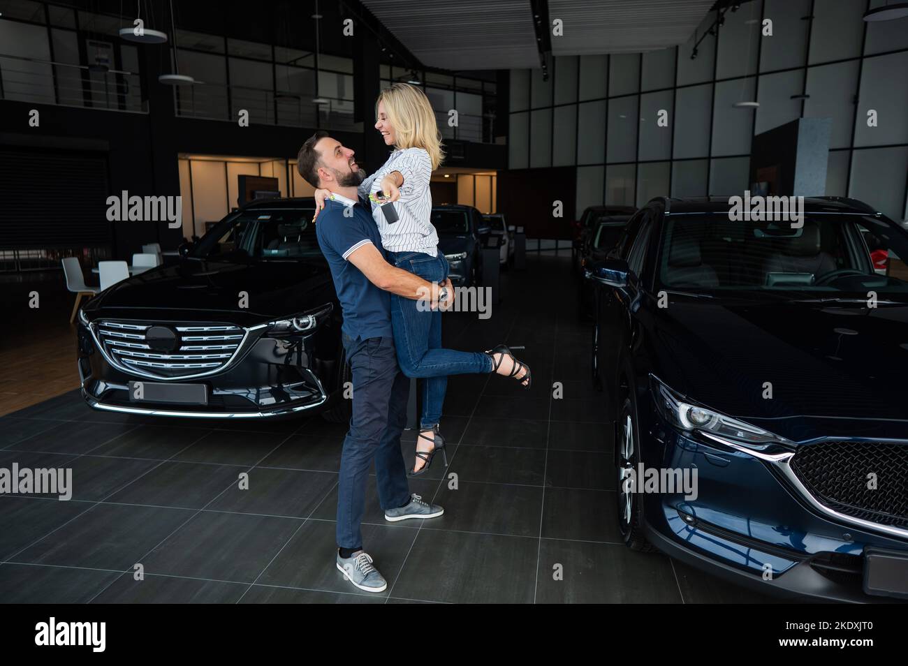 Happy caucasian couple hugging while buying a new car in a car ...