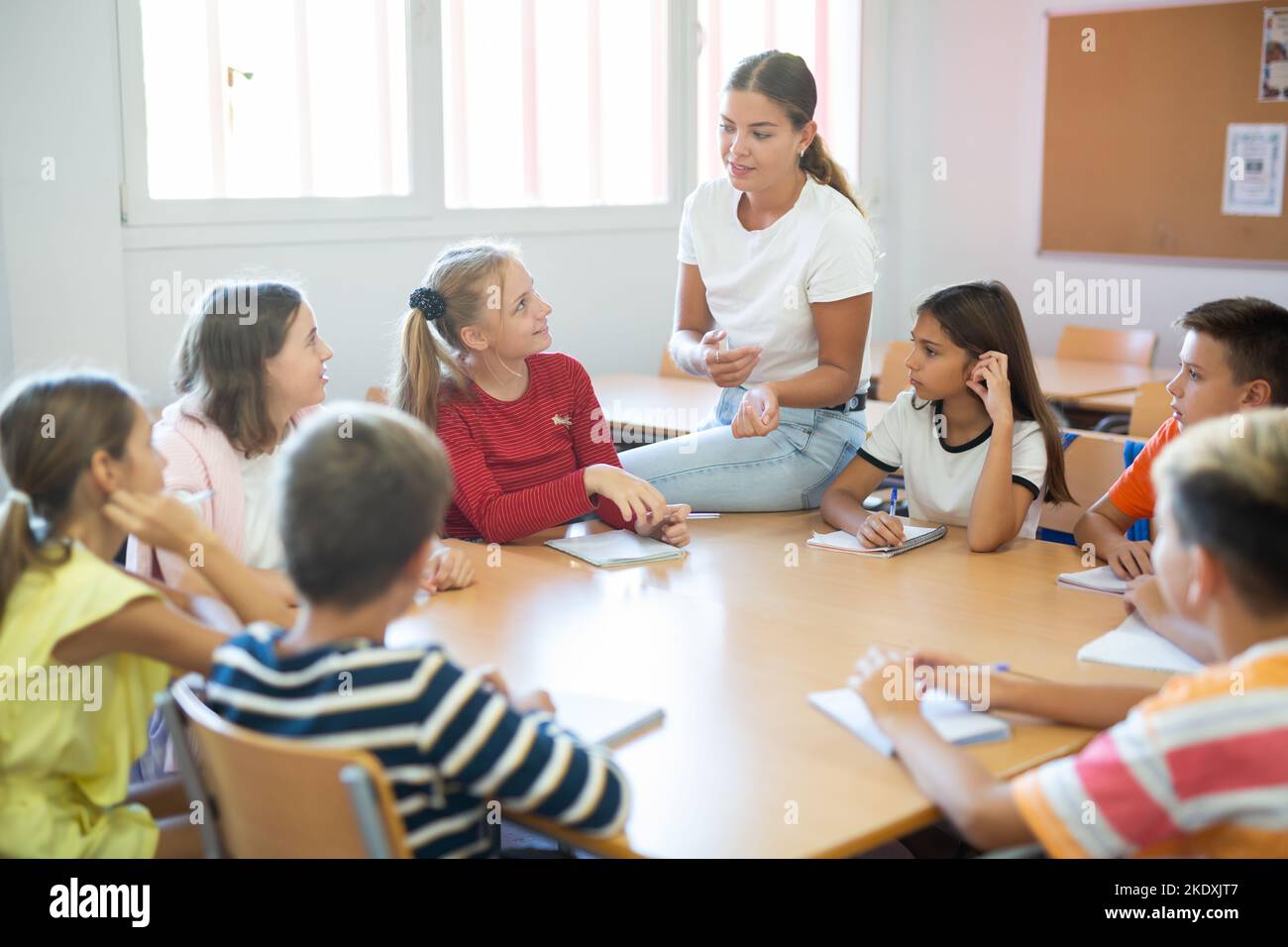Kids sitting around desk in classroom and studying during lesson Stock ...