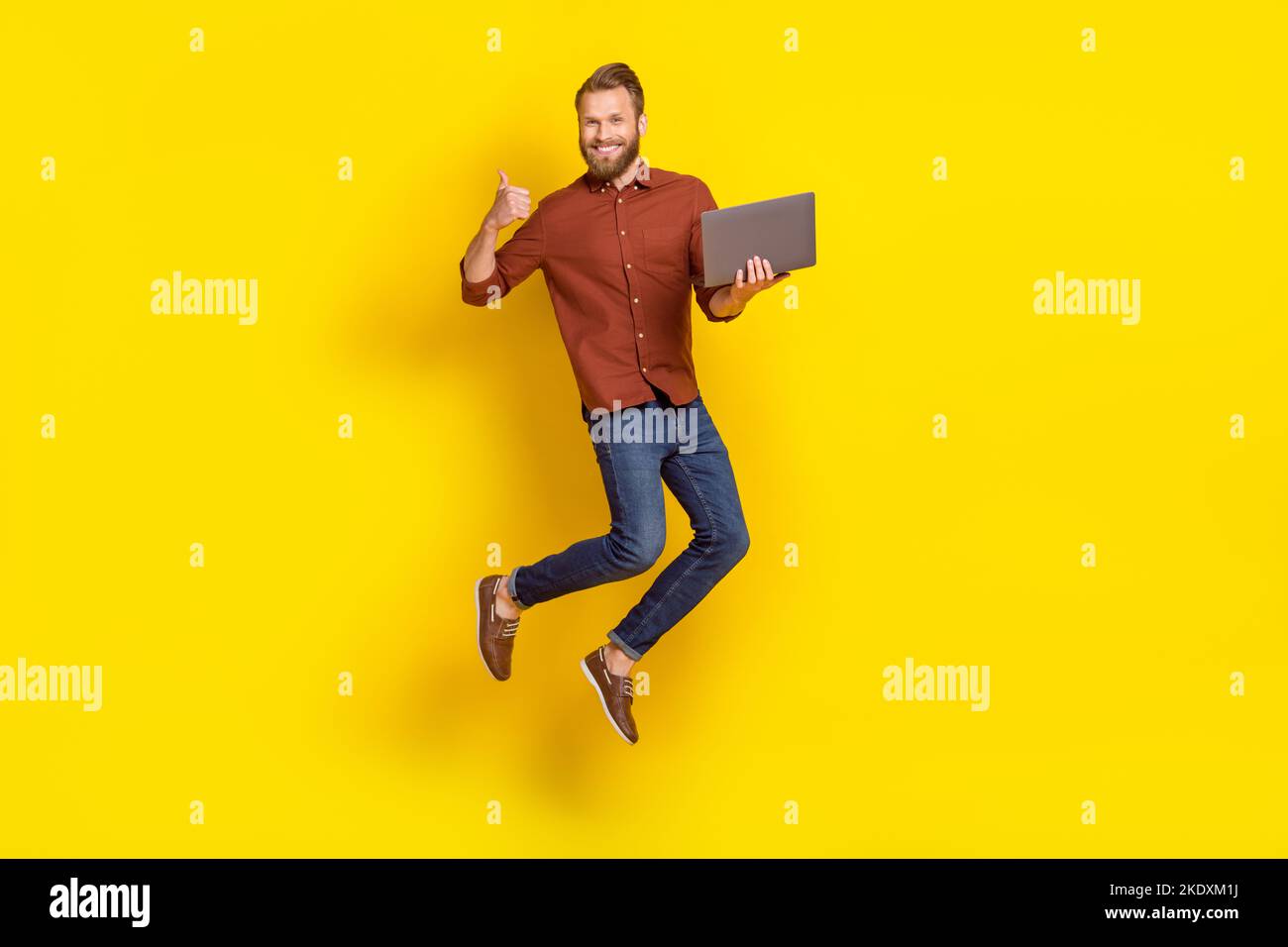 Full body portrait of handsome guy jumping hold netbook show thumb up ...