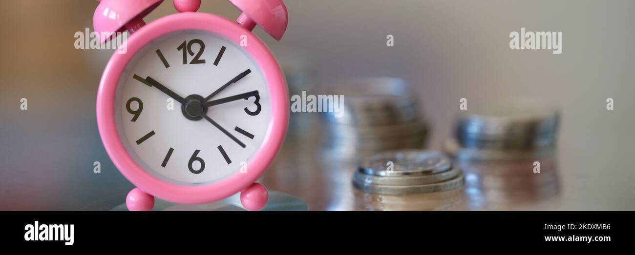 Alarm clock and money coin stack on table Stock Photo - Alamy