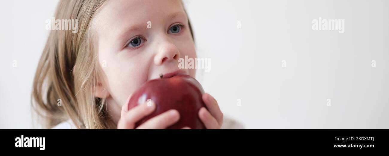 Little girl eating heartily fresh red apple Stock Photo - Alamy