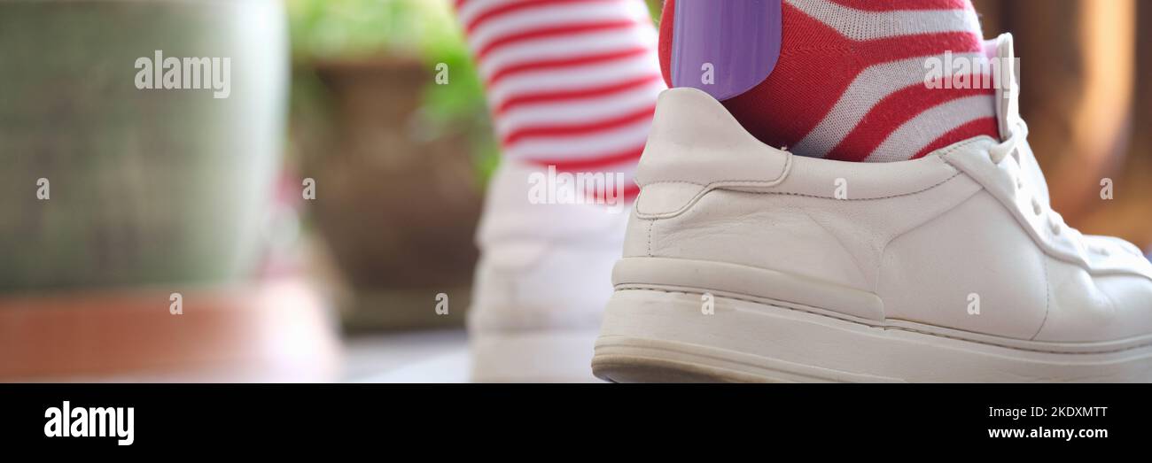 Person puts shoes white sneakers using shoehorn Stock Photo - Alamy