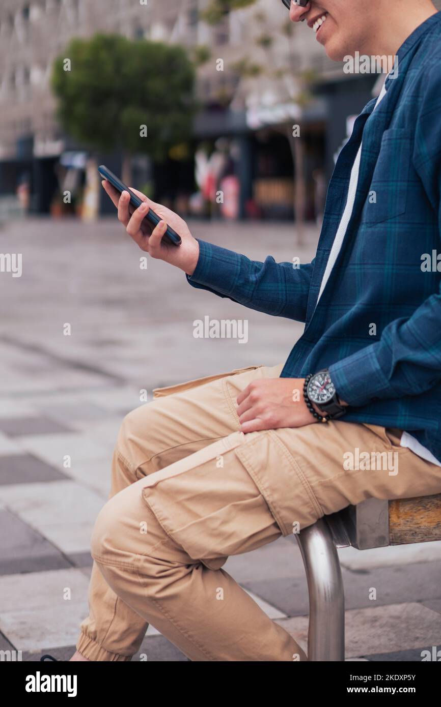 Cropped unrecognizable young man in casual clothes with smartphone ...