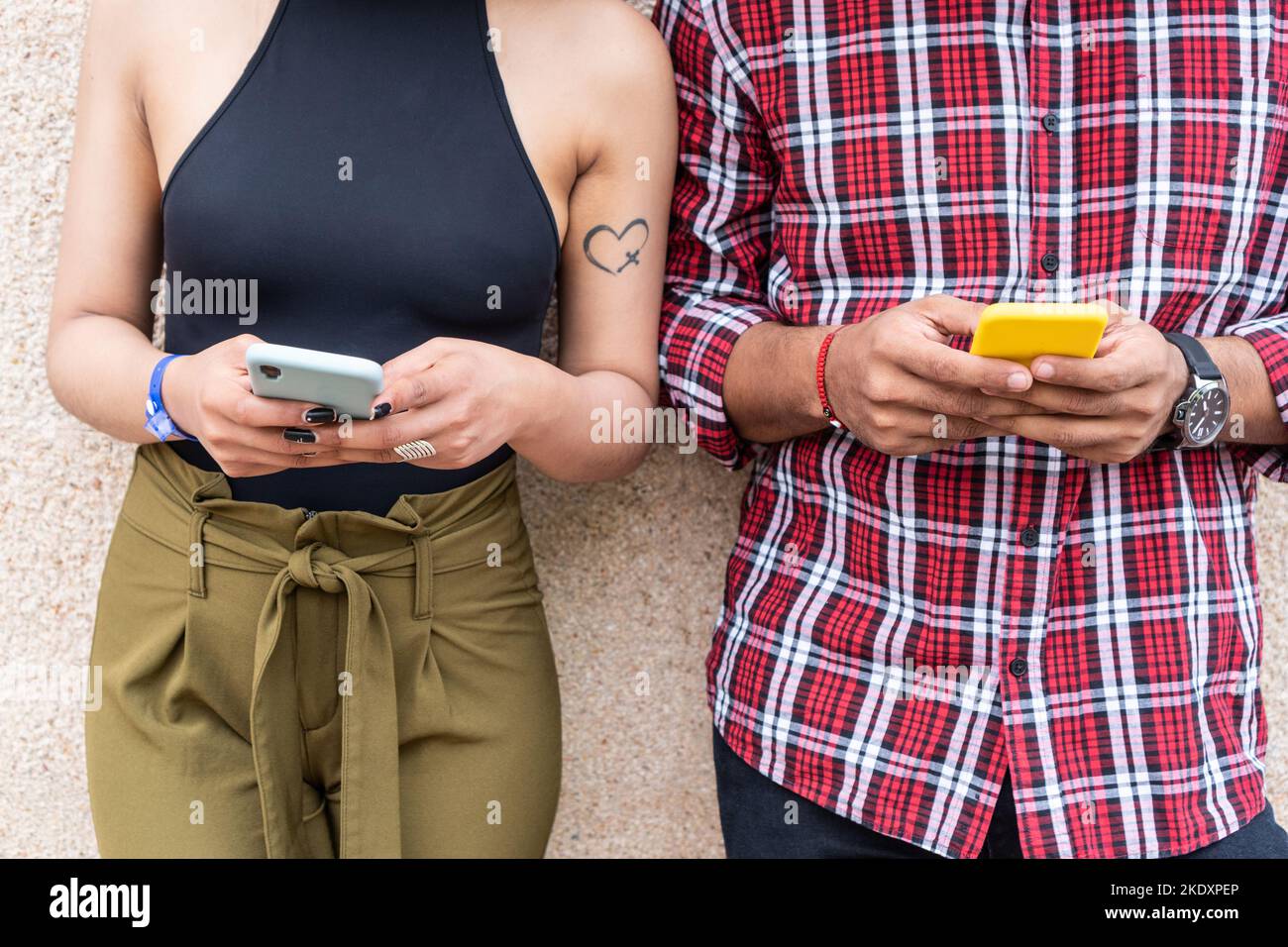 cropped unrecognizable couple in casual clothes browsing on smartphones ...