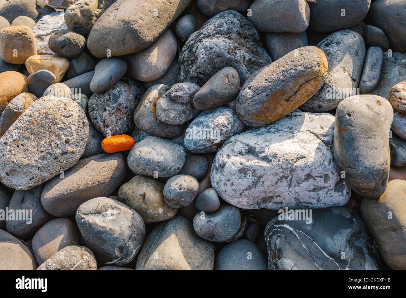 Full frame background of orange pebble located amidst smooth stones on ...
