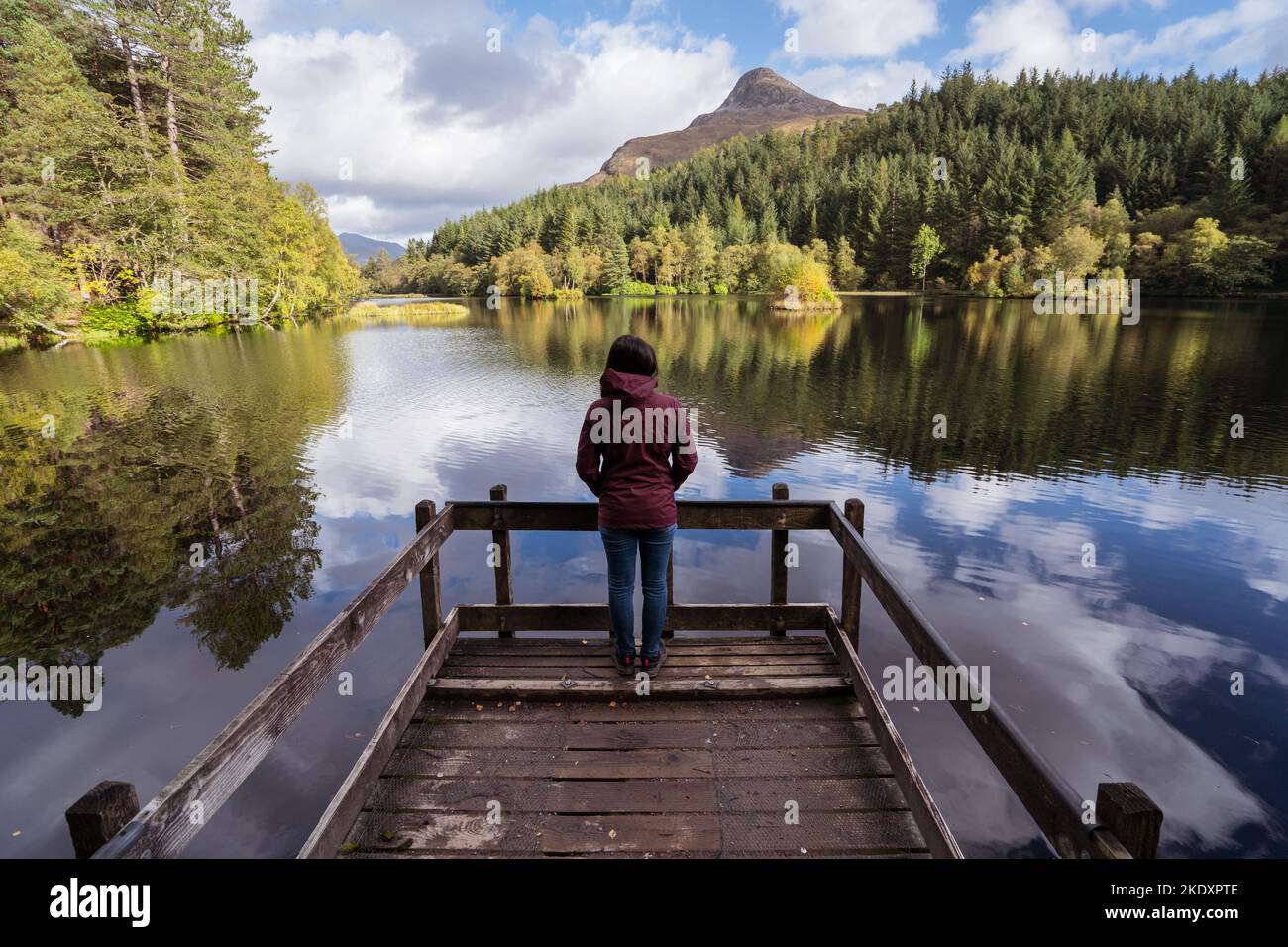Back view of unrecognizable female tourist standing on wooden quay near ...