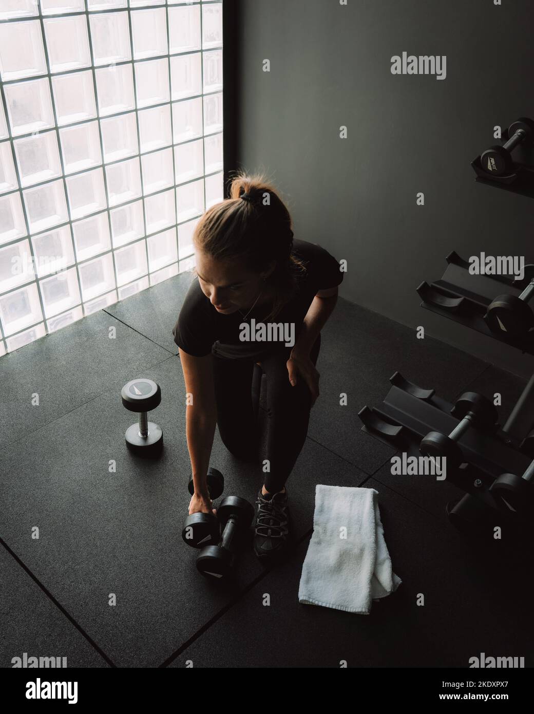 From above healthy female in activewear doing single arm row with ...