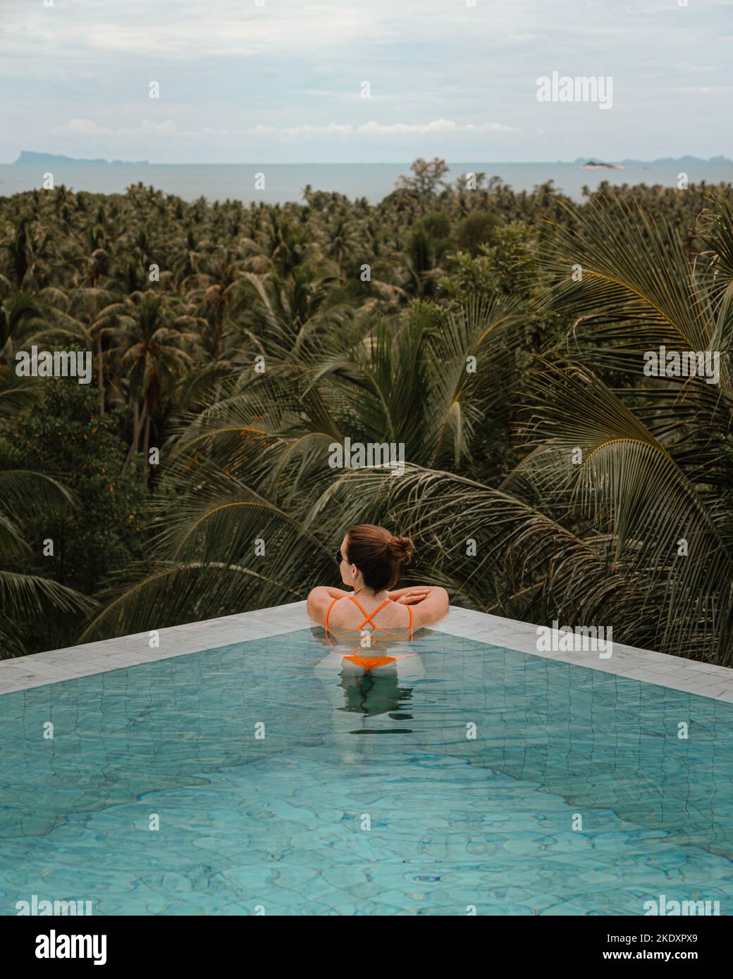 Back view of unrecognizable female tourist standing in corner of pool ...