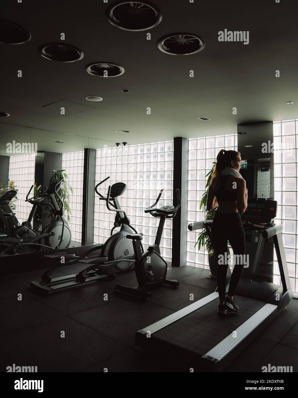 Back view of young sportive lady with towel on neck walking on ...