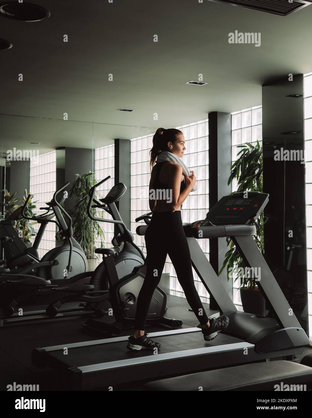 Back view of young sportive lady with towel on neck walking on ...