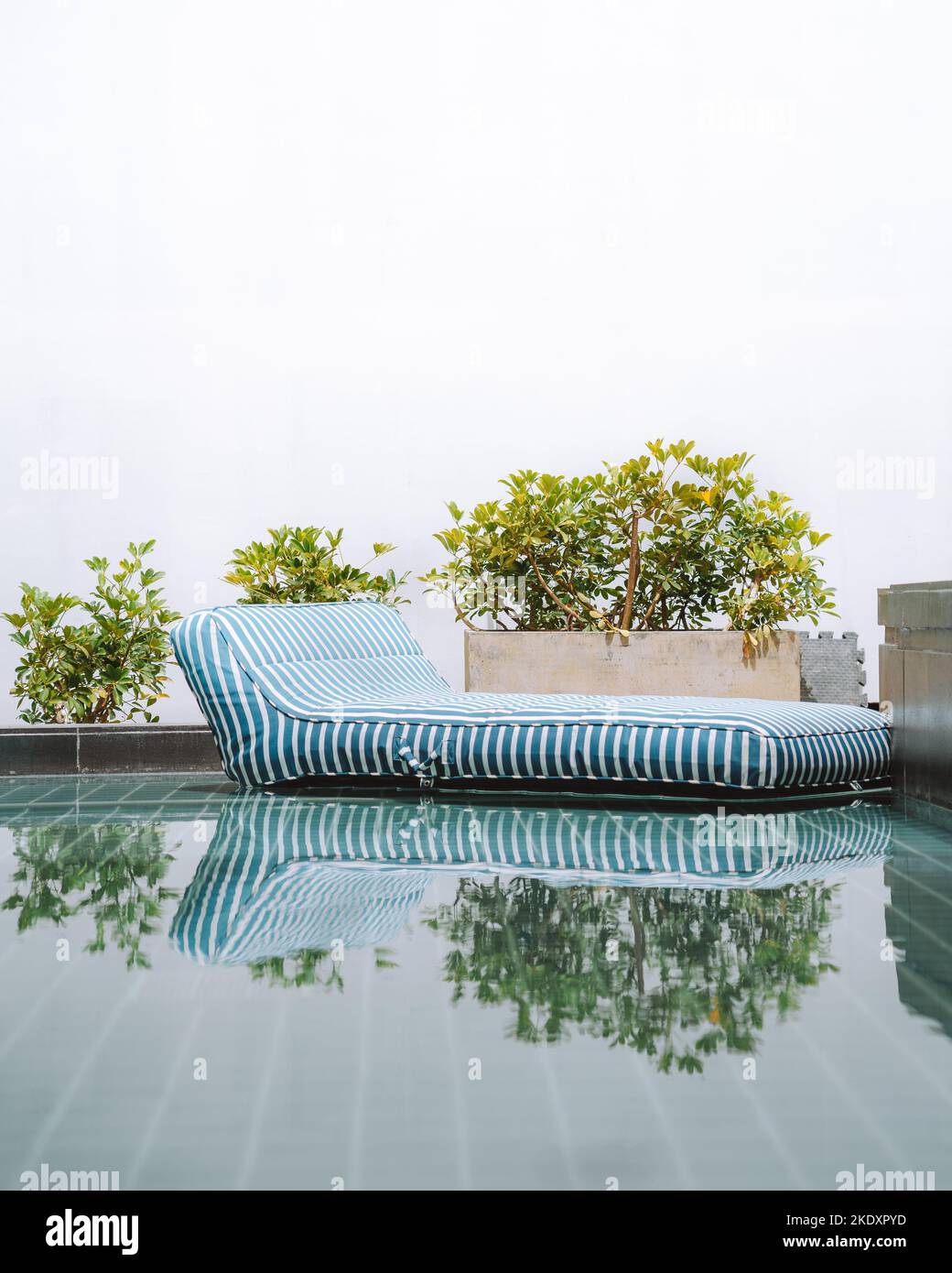Striped inflatable lounger on calm mirror surface of pool in resort ...
