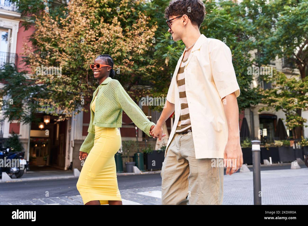 From below confident young multiethnic couple in stylish outfits and ...