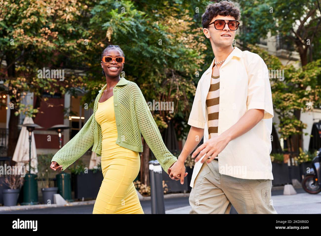 From below confident young multiethnic couple in stylish outfits and ...
