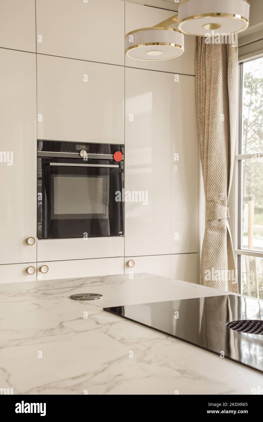 Modern built in oven installed into cupboards behind counter in sunlit ...