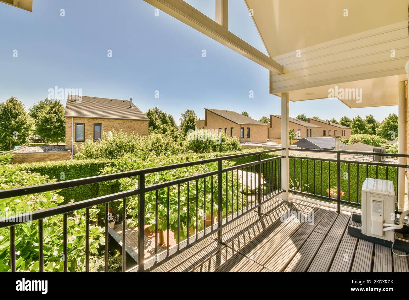 Views of multiple houses and backyard from metal balcony under blue sky ...