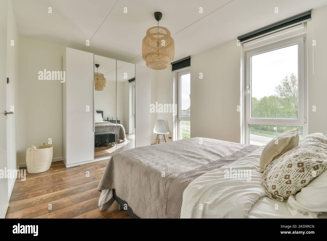 Comfortable bed next to a bright window and wooden floor Stock Photo ...
