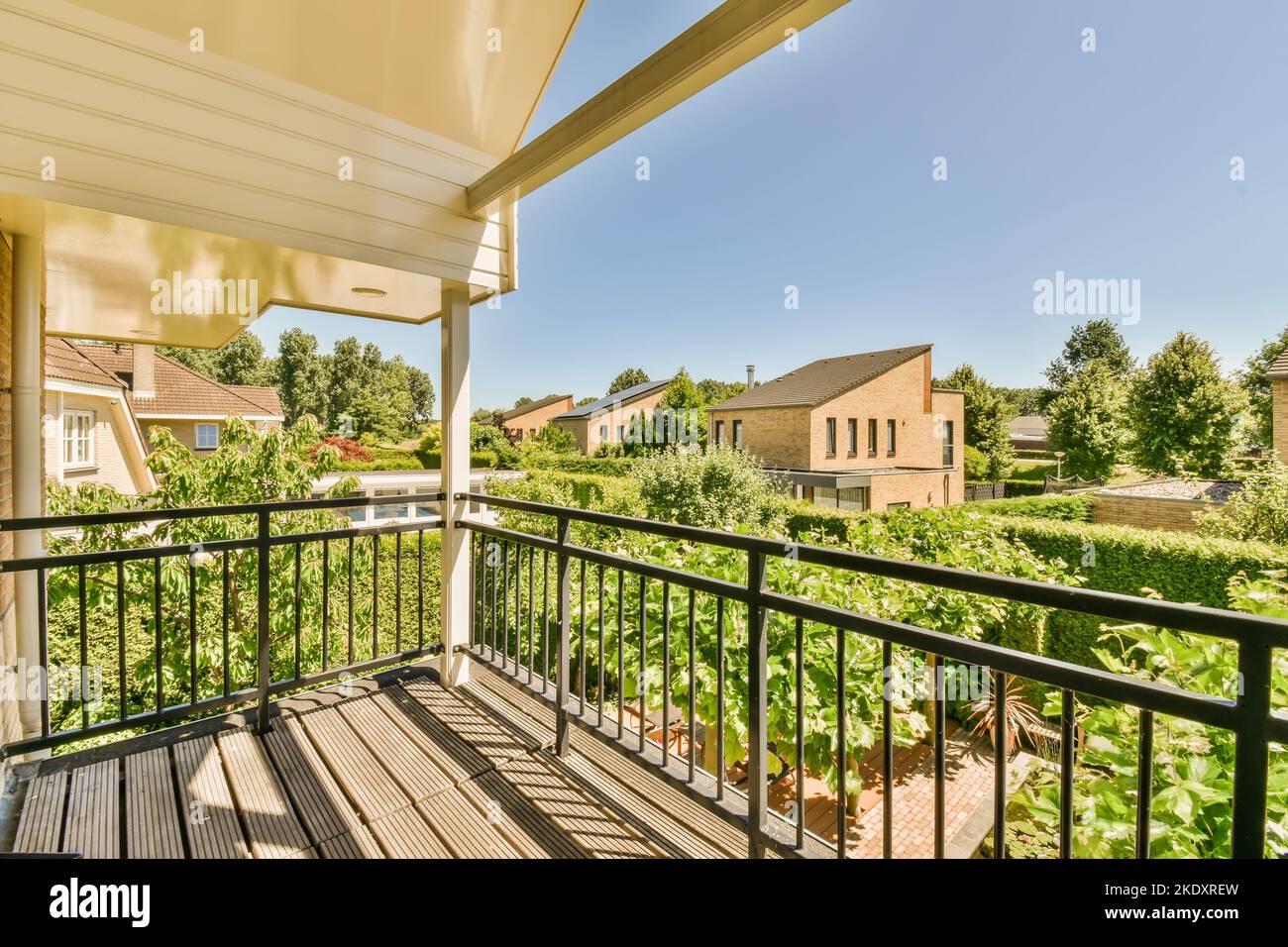 Views of multiple houses and backyard from metal balcony under blue sky ...