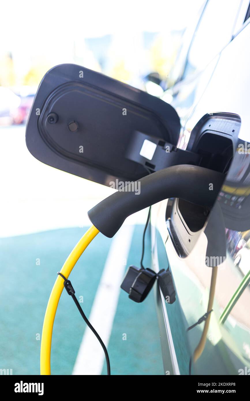 Detail of cable plugged into the electric car, charging the battery ...