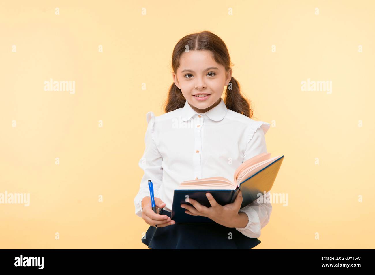 Child girl school uniform clothes hold book and pen. Girl cute write ...