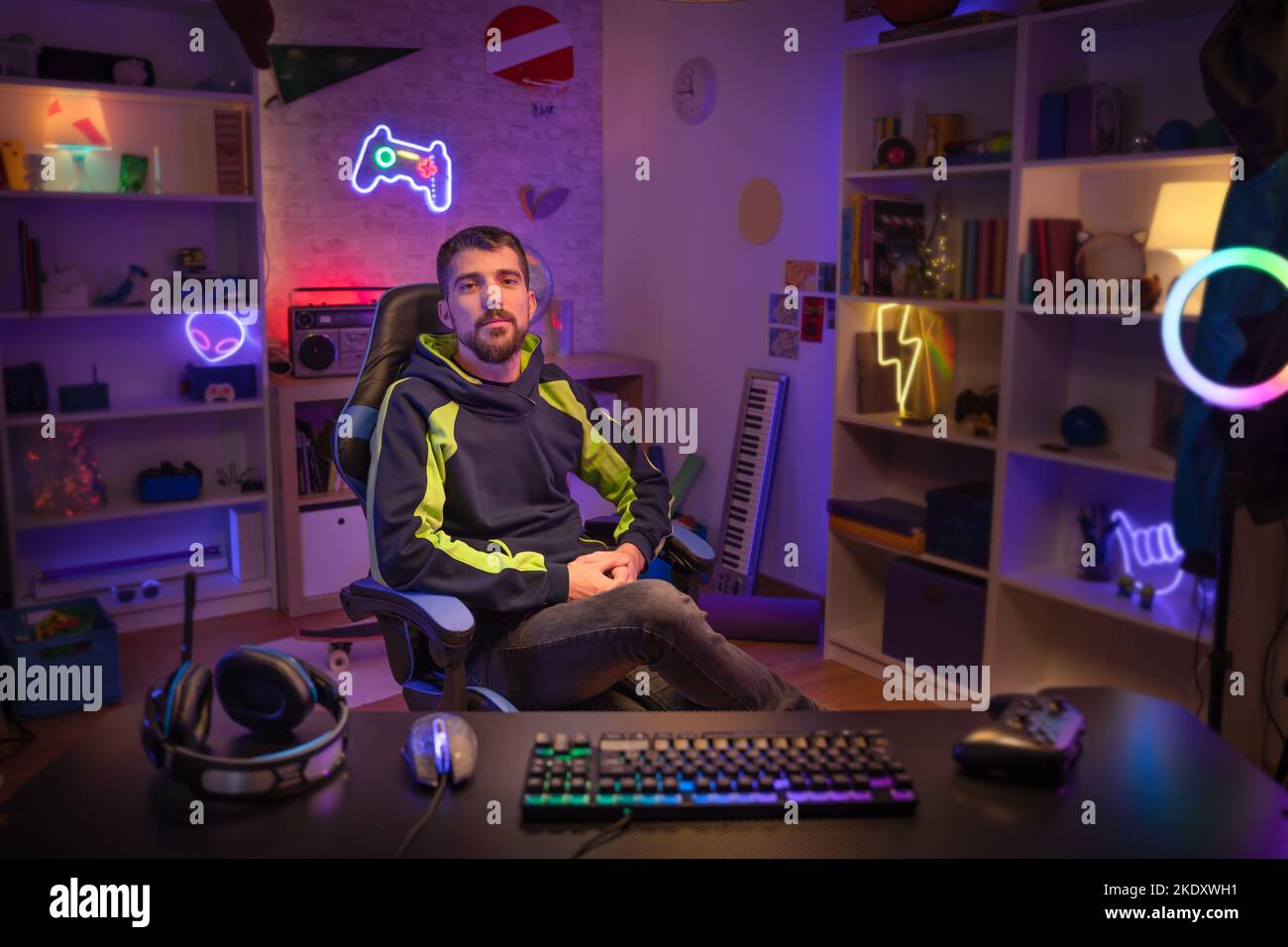 Gamer at his room portrait looking to the camera with Colorful Neon Led ...