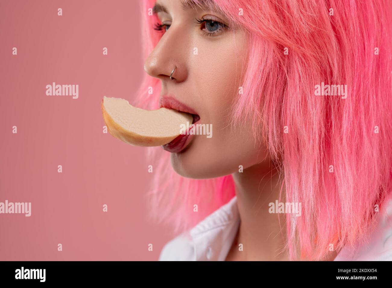 Young pink-haired female eating a healthy fruit Stock Photo - Alamy