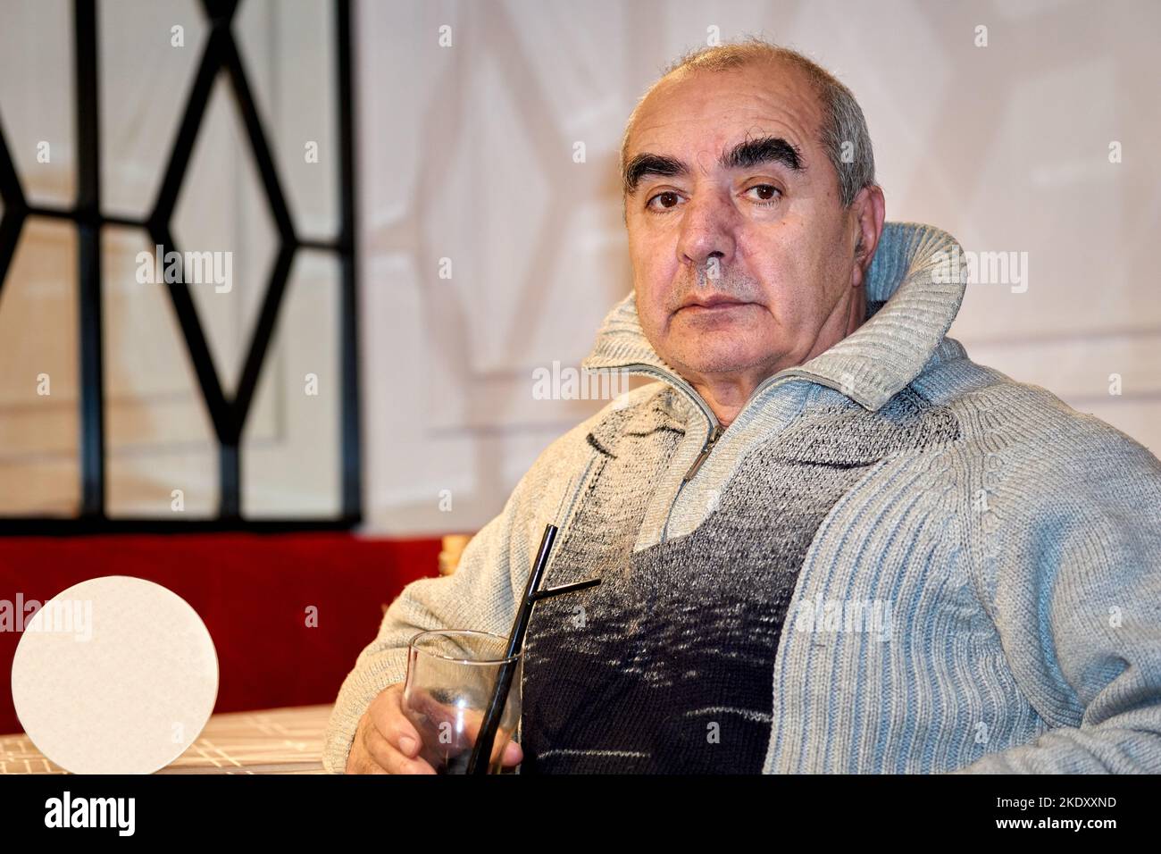 Elderly male pensioner sitting with a glass at a table in a cafe Stock ...