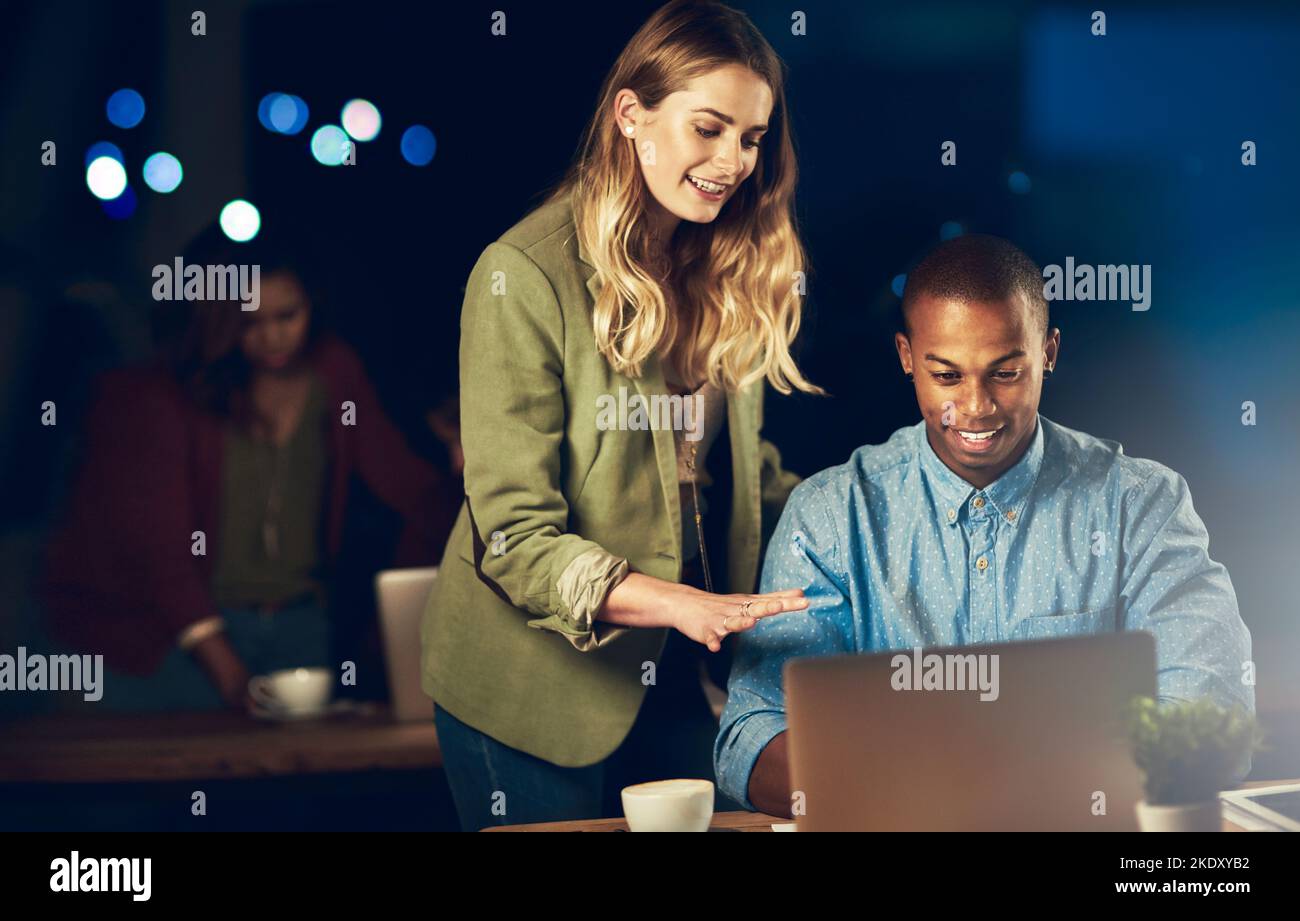 Giving him a little advice. two young colleagues working late in the ...