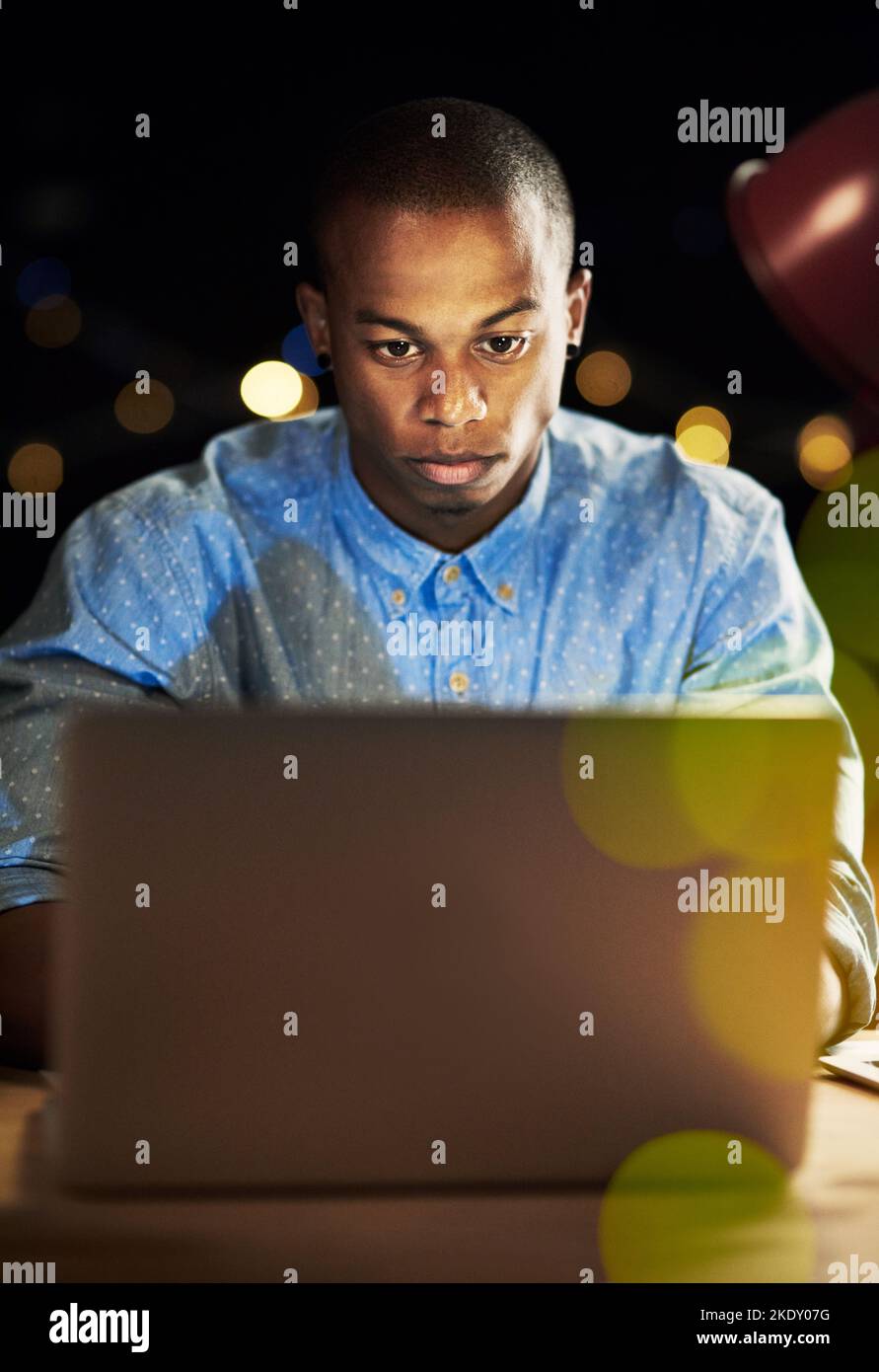 Focused on getting it done. a handsome young man working late night on ...