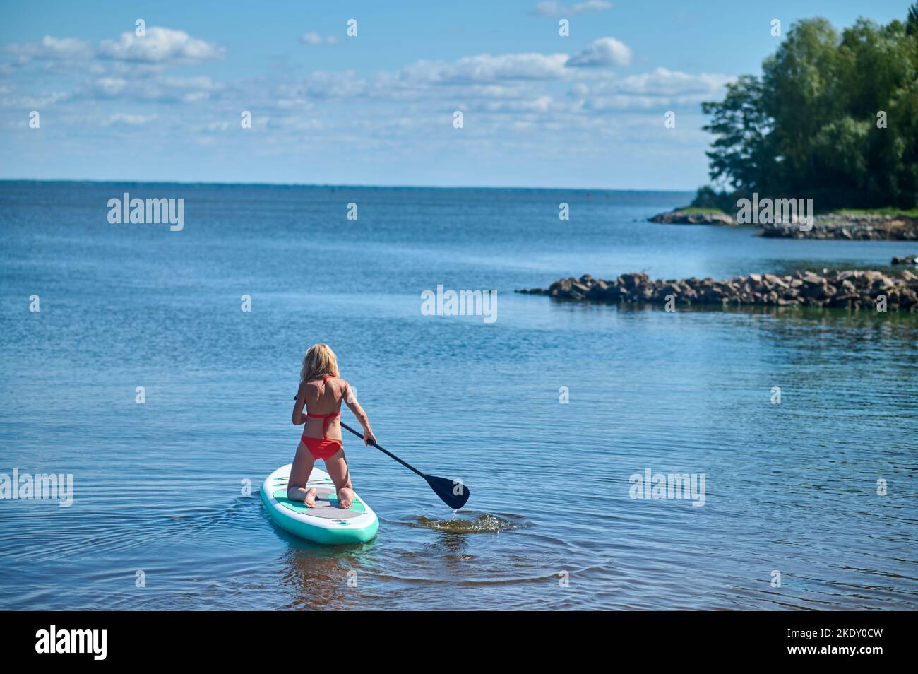 Active blonde woman in red swimming suit kayaking Stock Photo - Alamy