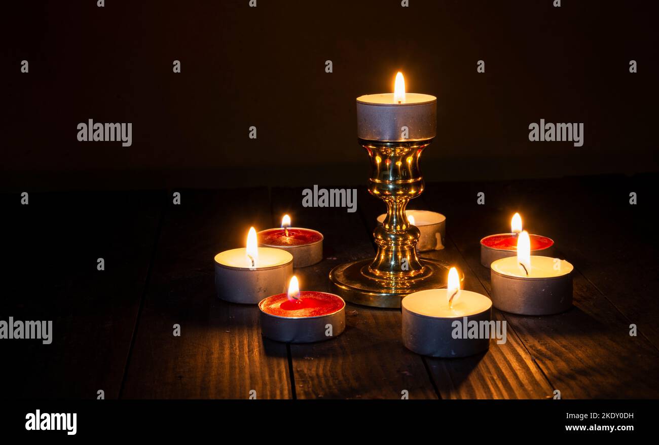 Multiple candles light with big stand on wood table dark background ...