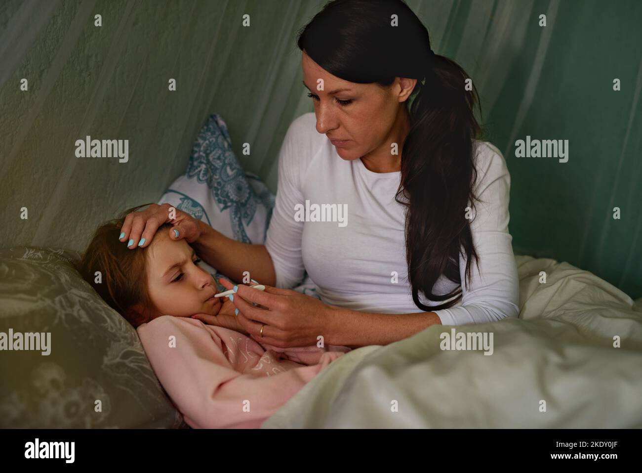 This fever may be a sign of an infection. a little girl lying in bed ...